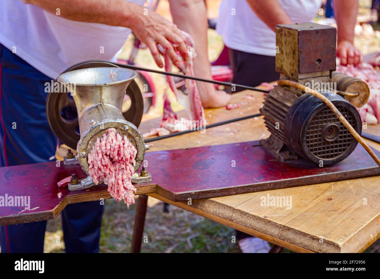 Men are working together on meat grinder machine, forcemeat process for ...