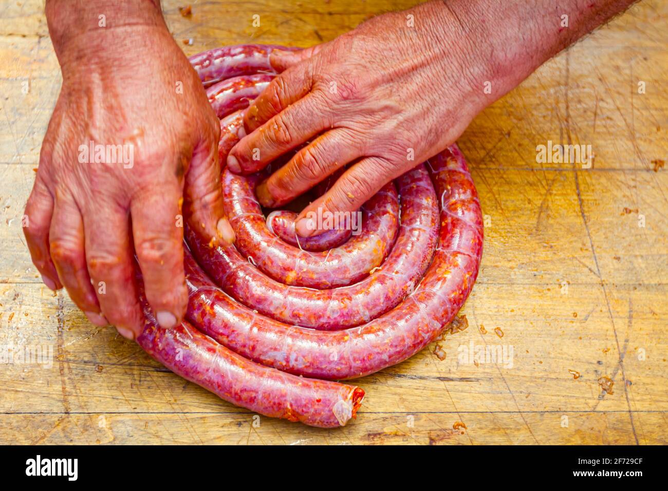Butcher twists fresh intestine filled with minced meat, divide to make ...