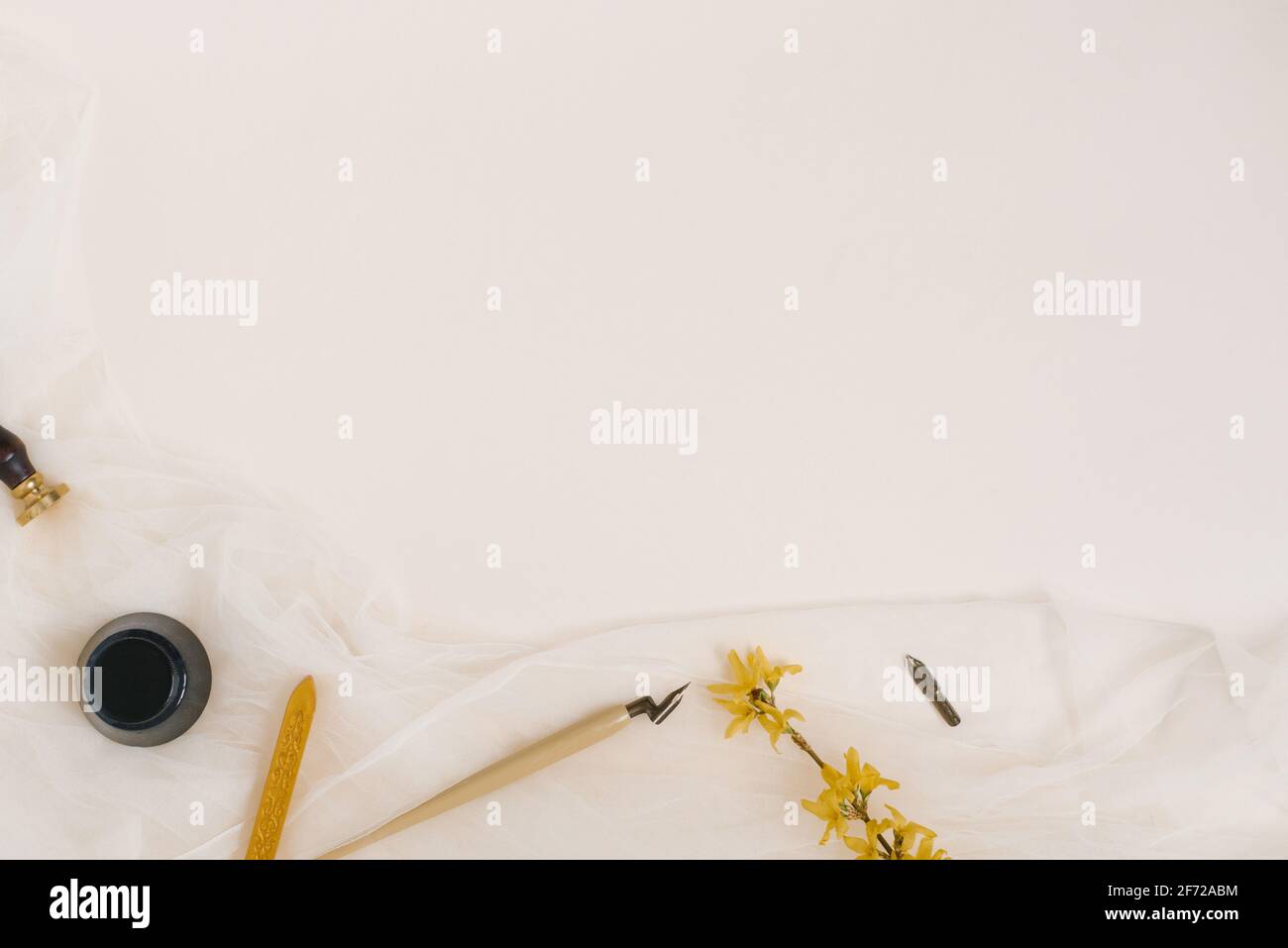 Calligraphy, sharp pen, ink, quills, yellow forsythia flower on beige ...