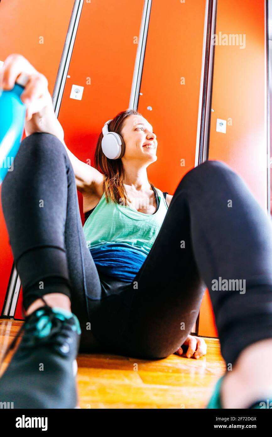 Beautiful fit young woman sitting in gym locker room resting smiling ...