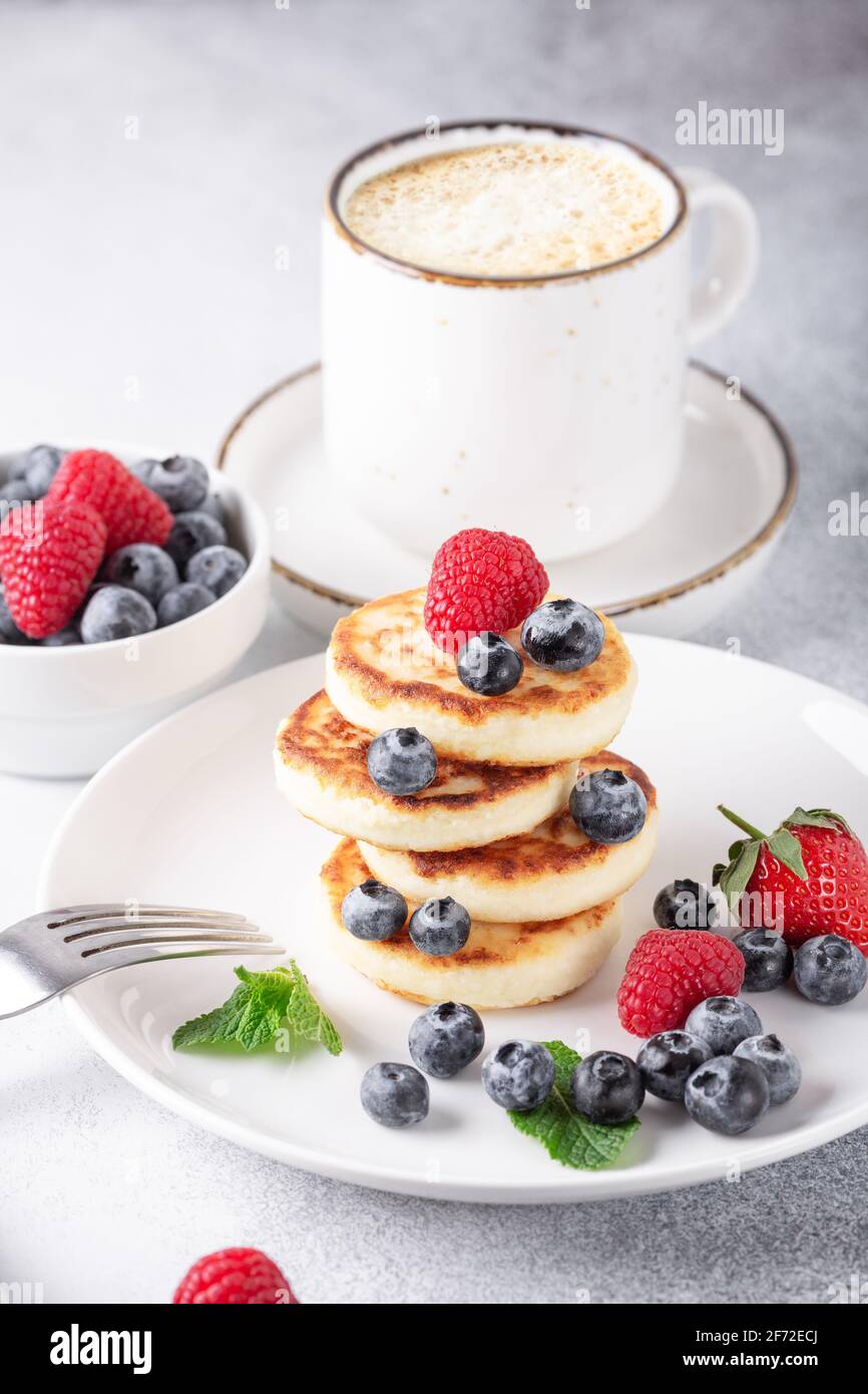 Stack of cheese pancakes with fresh berries, cup of coffee on the table ...
