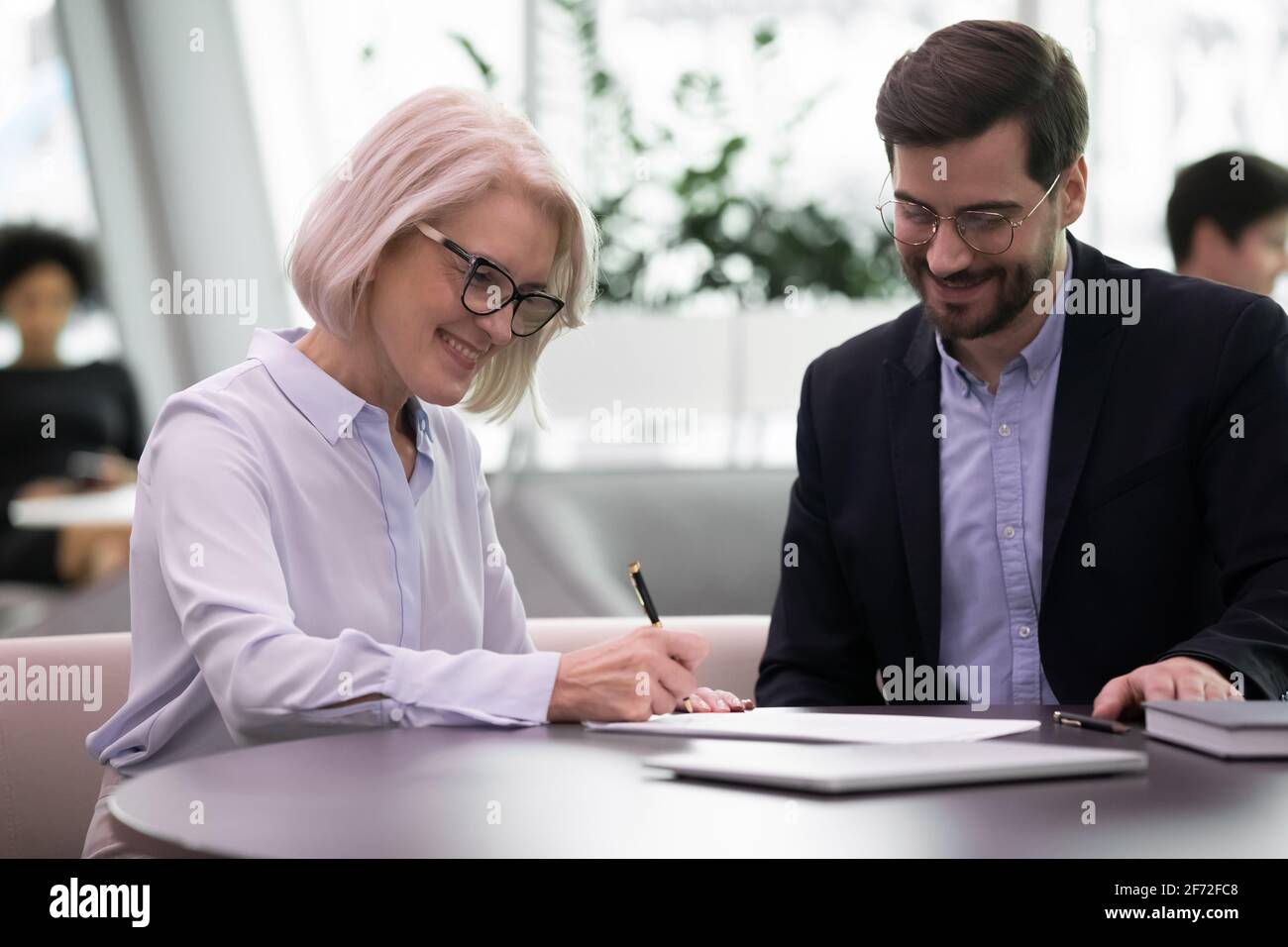 Smiling middle-aged female client sign deal with partner Stock Photo ...