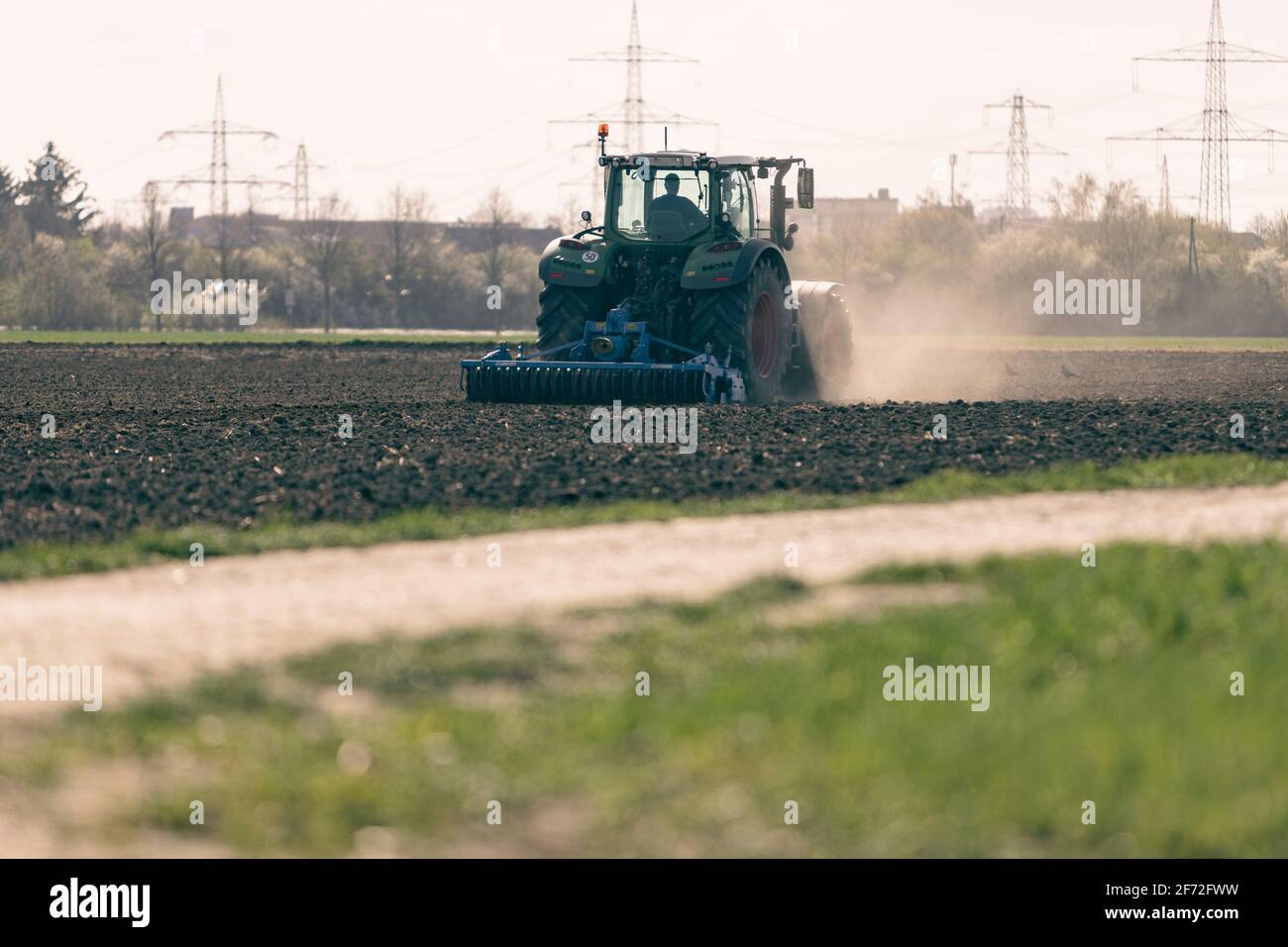 Huerth, NRW, Germany, 04 03 2021, tractor with harrow on a field, dust ...