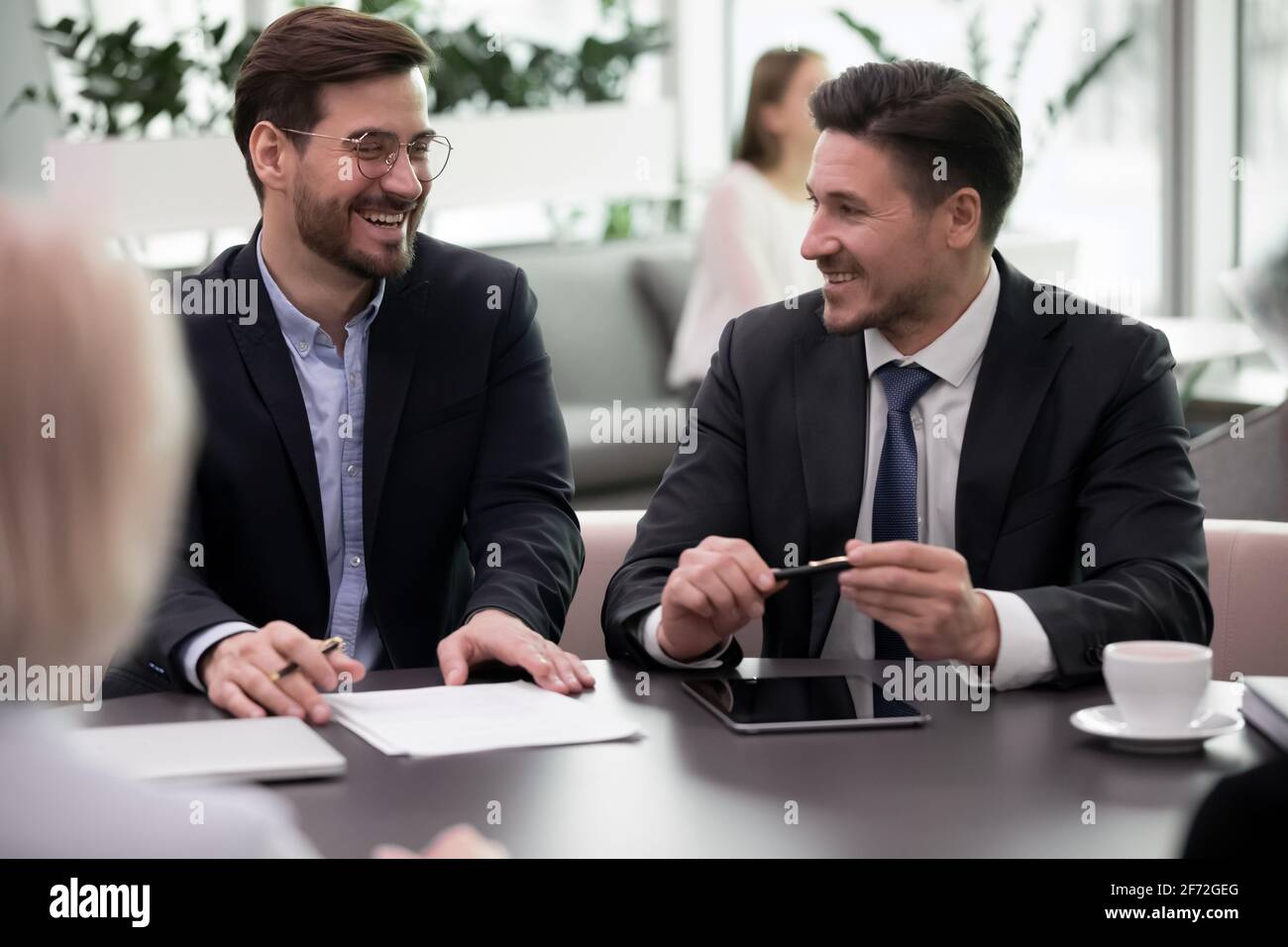 Smiling businessmen laugh brainstorming at office meeting Stock Photo ...