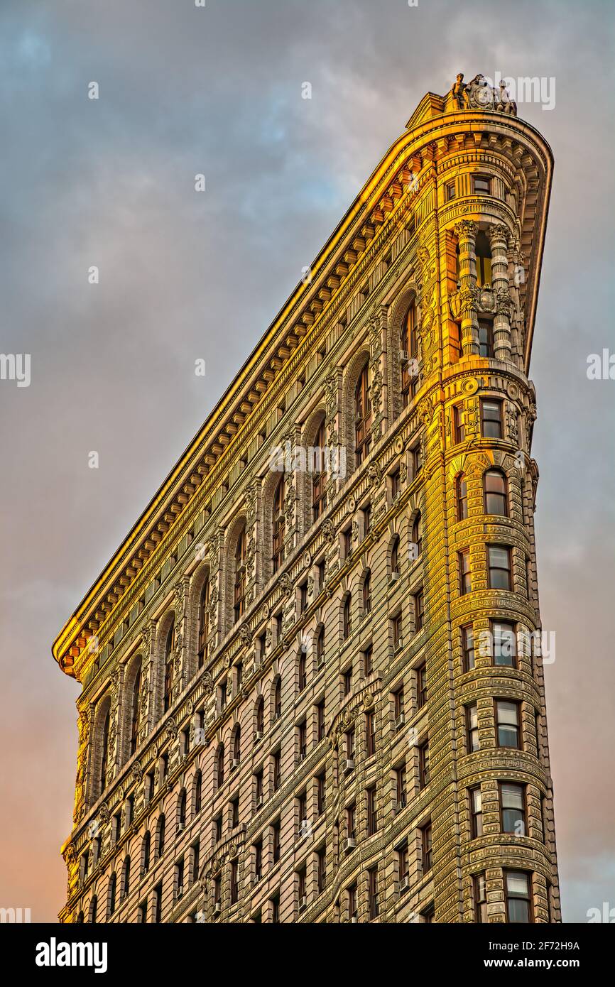 Iconic Flatiron Building, with edge lit by first rays of morning sun ...