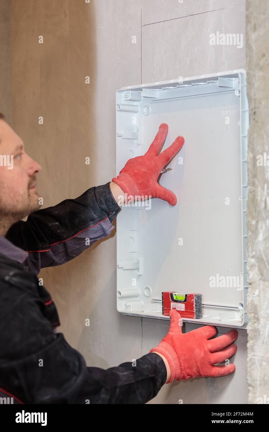 The electrician tries on and marks the lines of the electrical panel ...