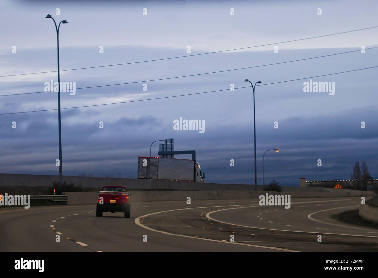 a bright red pickup truck on a curving freeway in the morning with ...