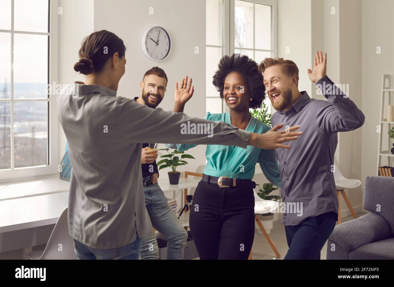 Group of excited young people congratulating friend and coworker on ...