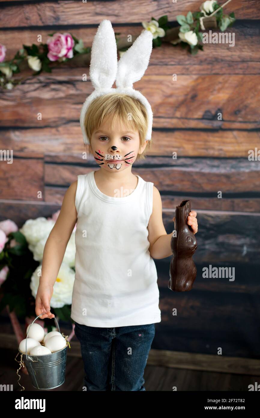 Little toddler boy, child with rabbit painted on the face, eating ...
