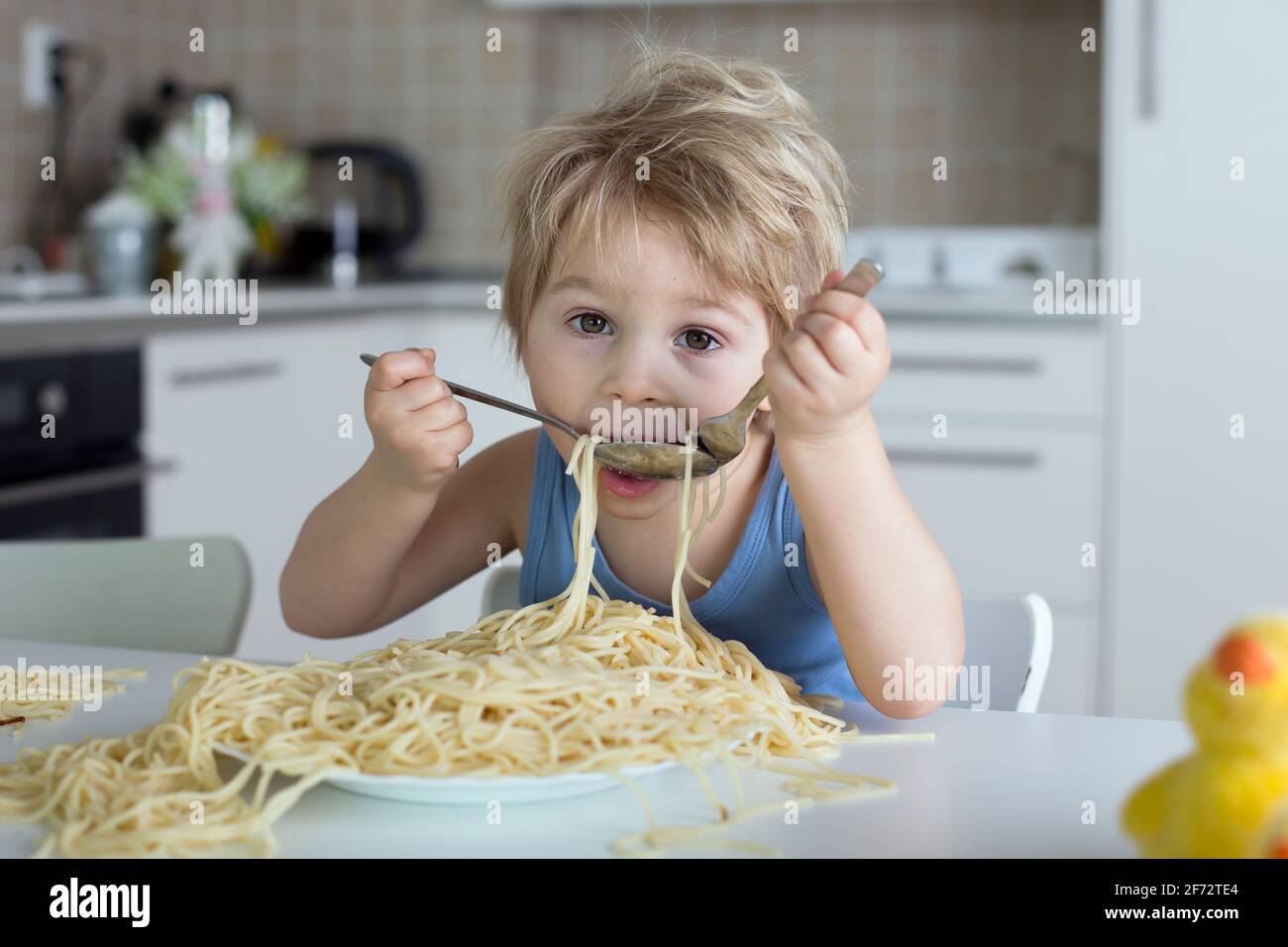 Little blond boy, toddler child, eating spaghetti for lunch and making ...