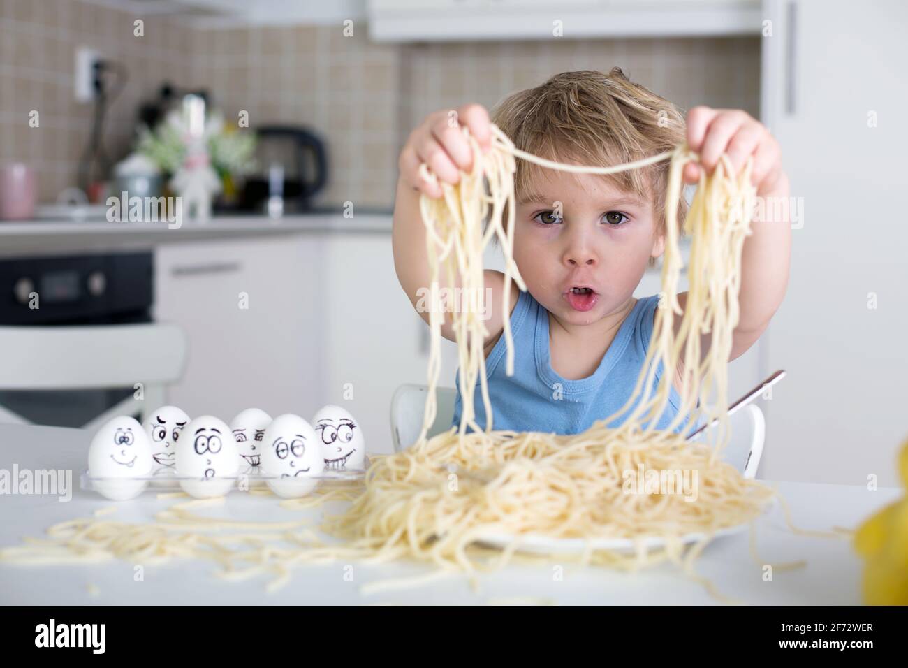 Little blond boy, toddler child, eating spaghetti for lunch and making ...
