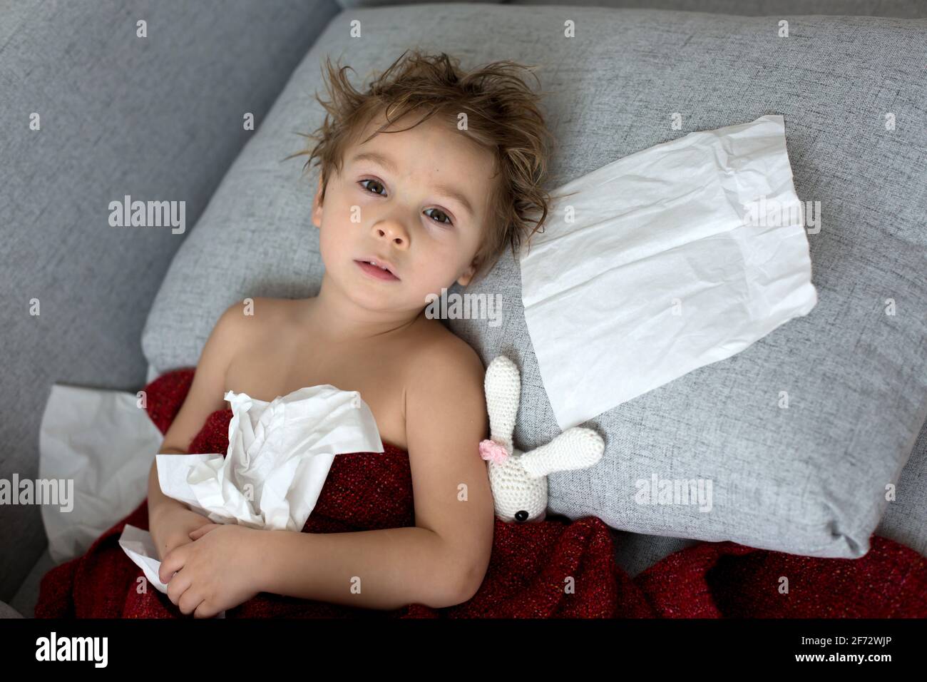 Toddler child, boy, lying sick on the sofa, mother checking him Stock ...