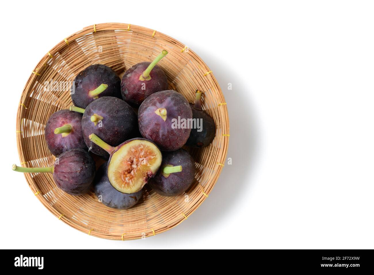 Fresh purple fig fruit and slices in bamboo basket isolated on white ...