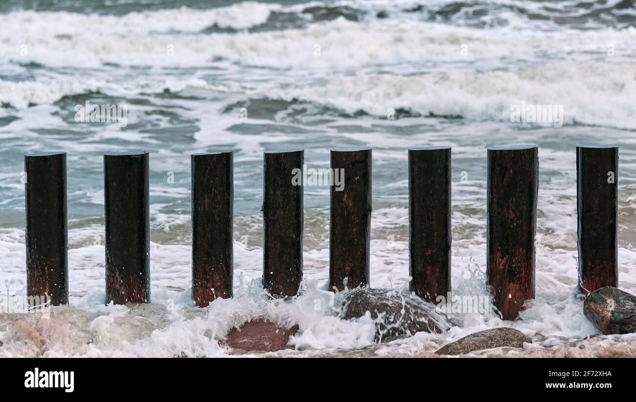 High wooden breakwaters in blue splashing sea waves, close up view ...