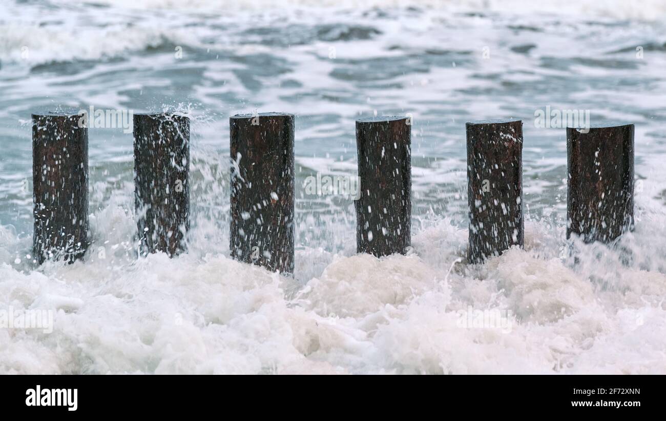 High wooden breakwaters in blue foaming sea waves, close up view. Long ...