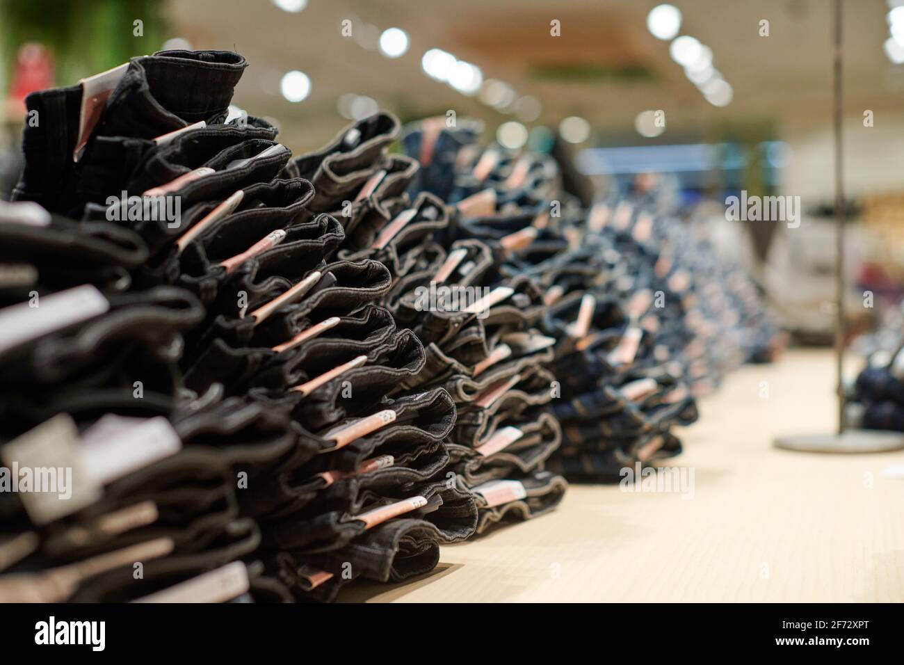 Denim jeans stack on wooden table on top in clothing store in modern ...