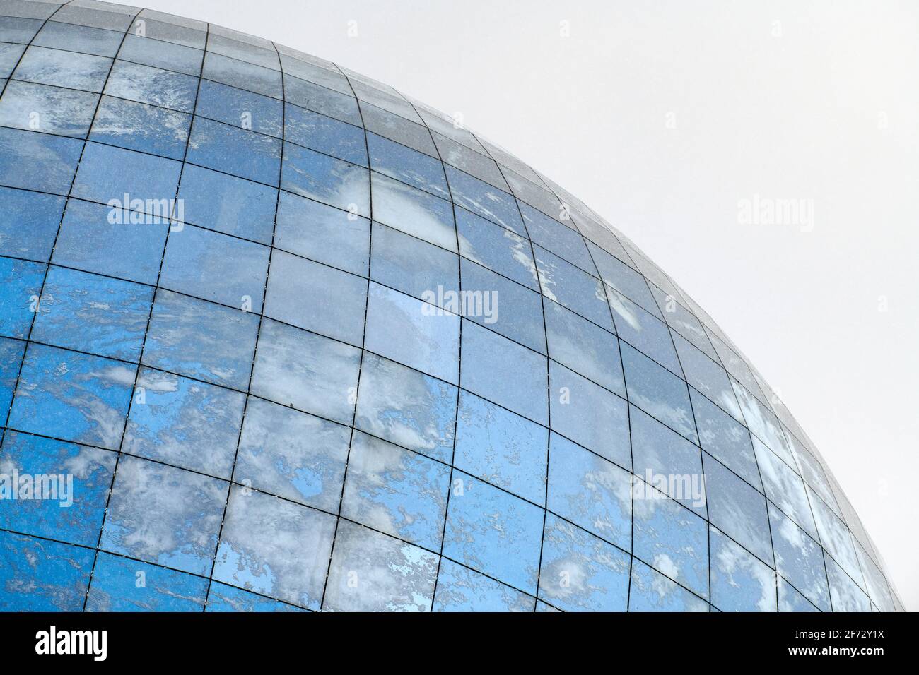 Glass spherical modern building with reflection of blue sky and clouds ...