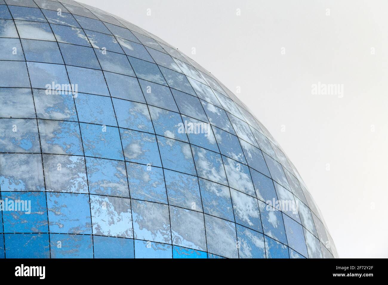 Glass spherical modern building with reflection of blue sky and clouds ...