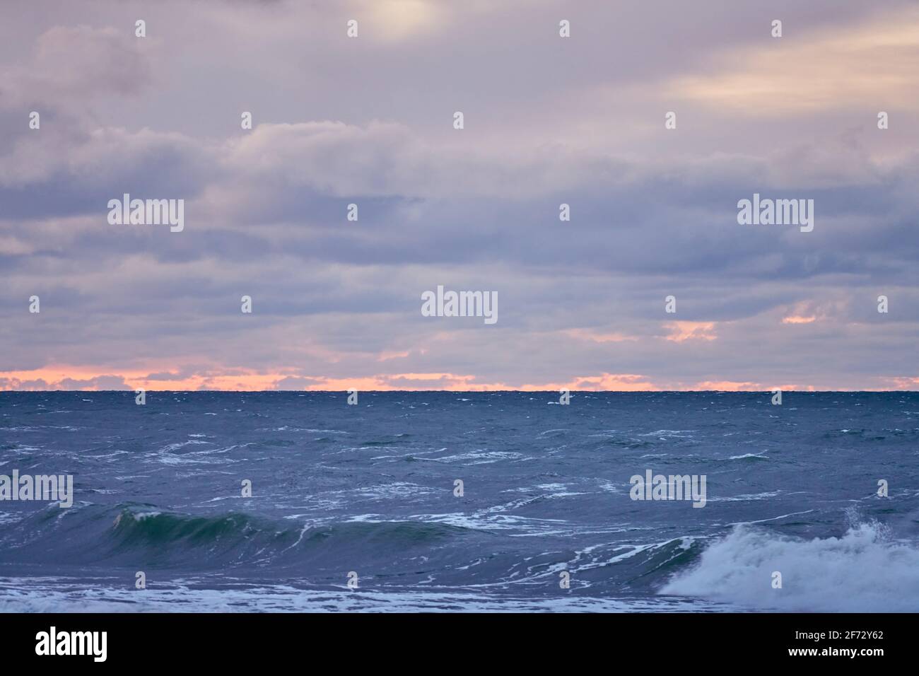 Scenic view of purple cloudy sky and blue sea with foaming waves. Windy ...