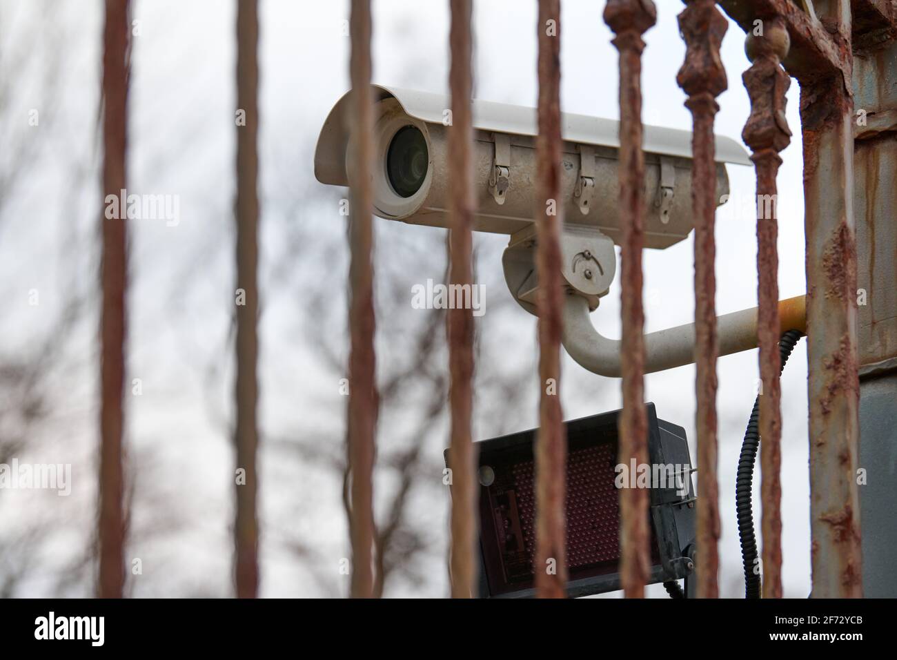 IP CCTV security camera and iron fence on grey sky background ...