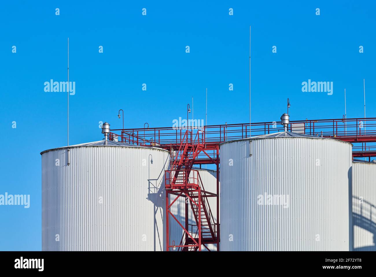 White fuel storage tanks against blue sky background. Large white ...