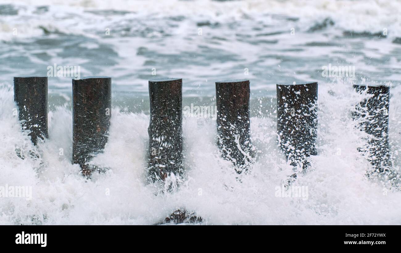 High wooden breakwaters in blue splashing sea waves, close up view ...