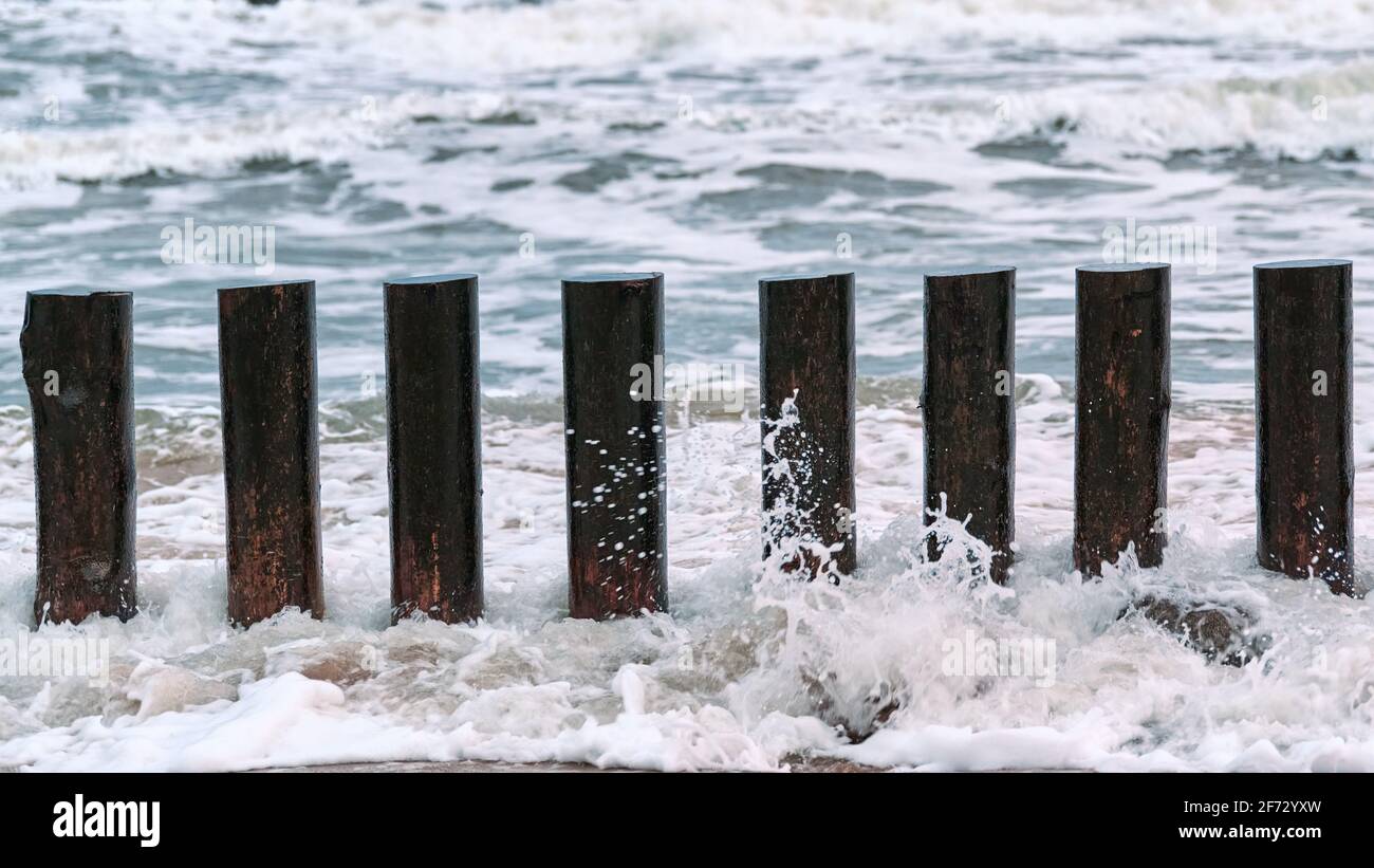 High wooden breakwaters in blue splashing sea waves, close up view ...