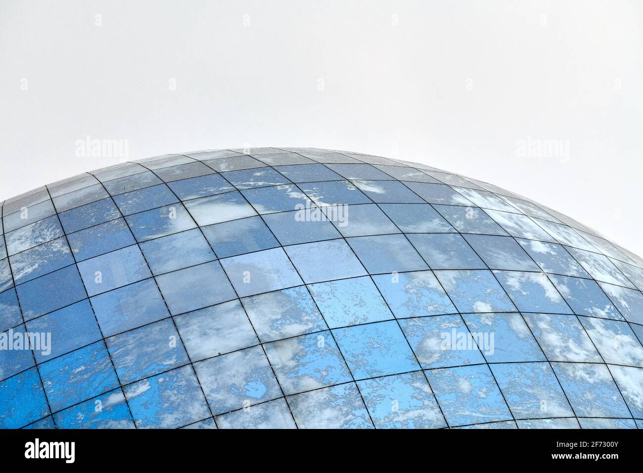 Glass spherical modern building with reflection of blue sky and clouds ...