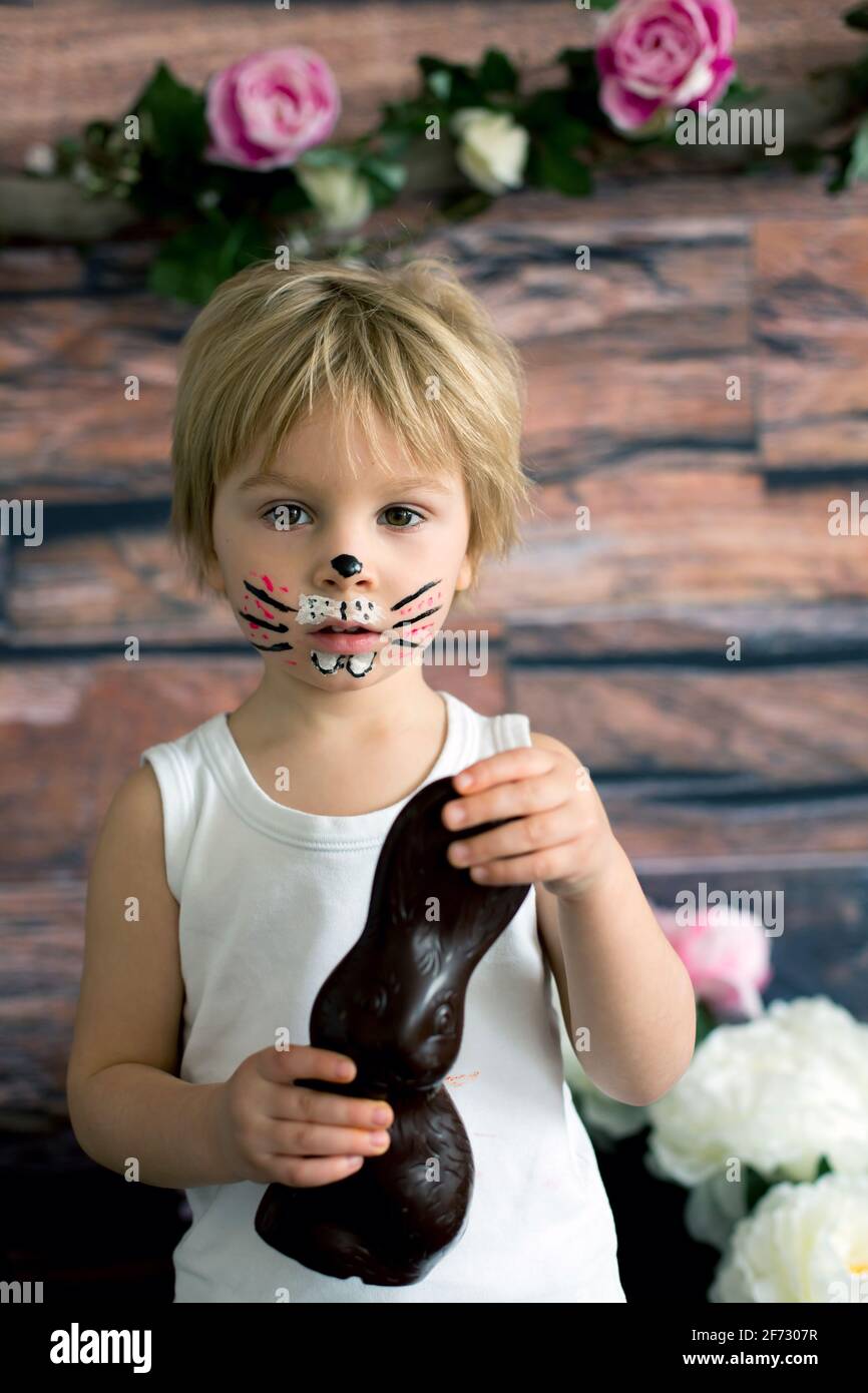Little toddler boy, child with rabbit painted on the face, eating ...