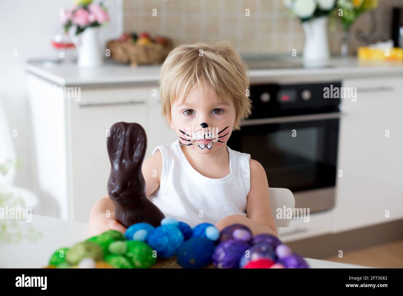 Little toddler boy, child with rabbit painted on the face, eating ...