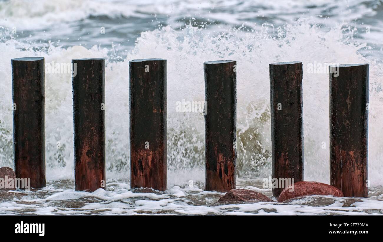 High wooden breakwaters in blue splashing sea waves, close up view ...