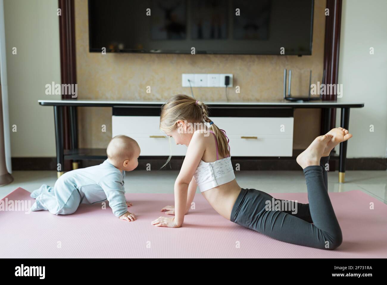 Cute little girl in sportswear doing fitness exercises at home. Distant ...