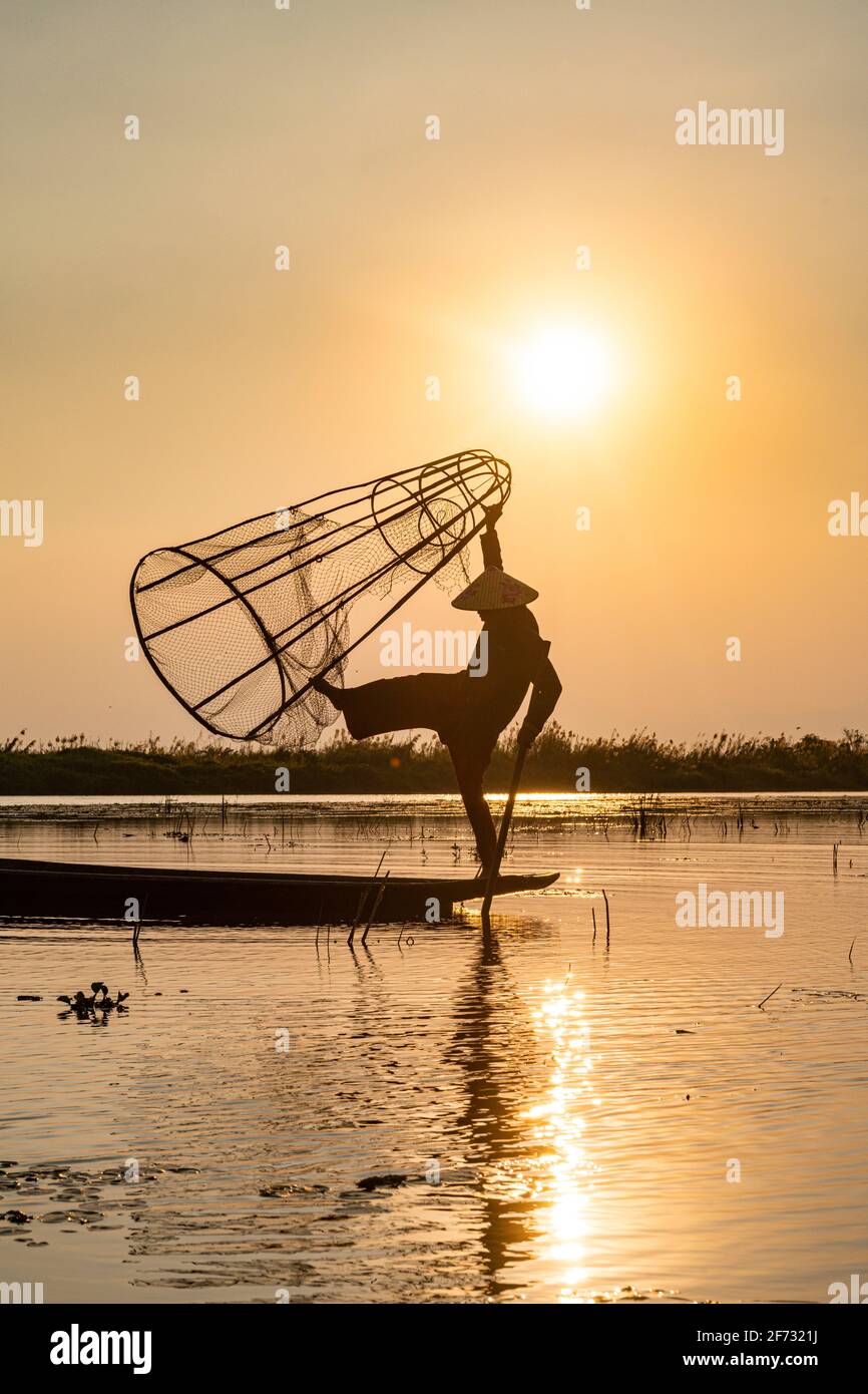 Fisherman at Inle Lake with traditional Intha conical net at sunset ...