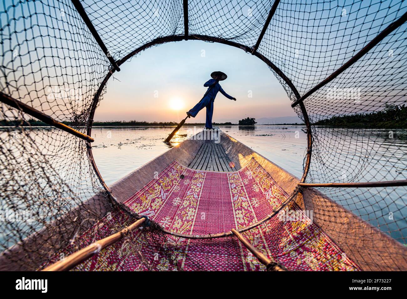 Fisherman at Inle Lake with traditional Intha conical net at sunset ...