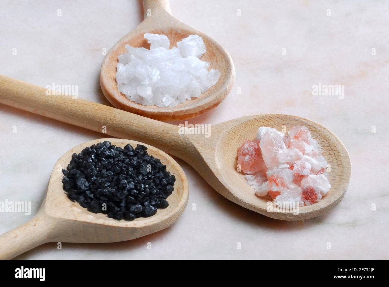Different kinds of salt on wooden spoons, crystal salt, Himalayan salt ...