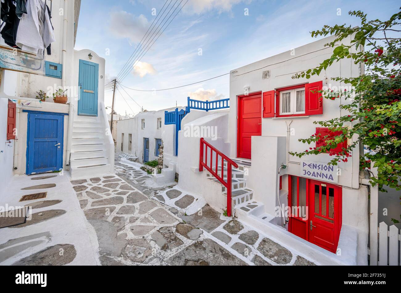 Small alley with white Cycladic houses with colorful shutters and doors ...