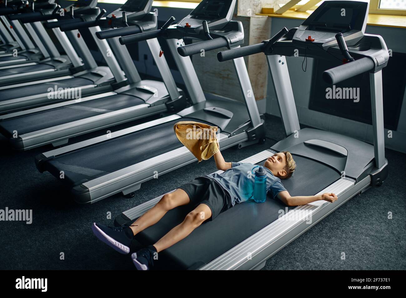Tired youngster lying on treadmill in gym Stock Photo - Alamy