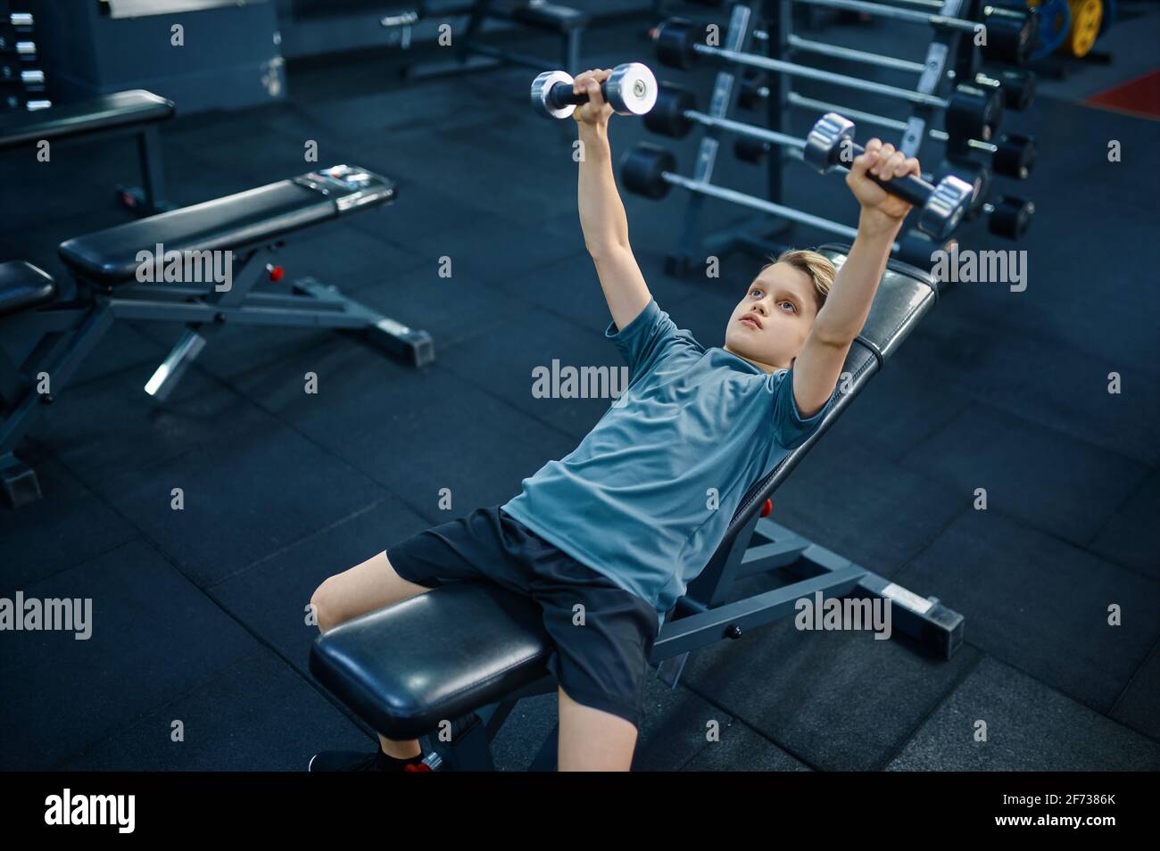 Boy doing exercise with dumbbells on bench Stock Photo - Alamy
