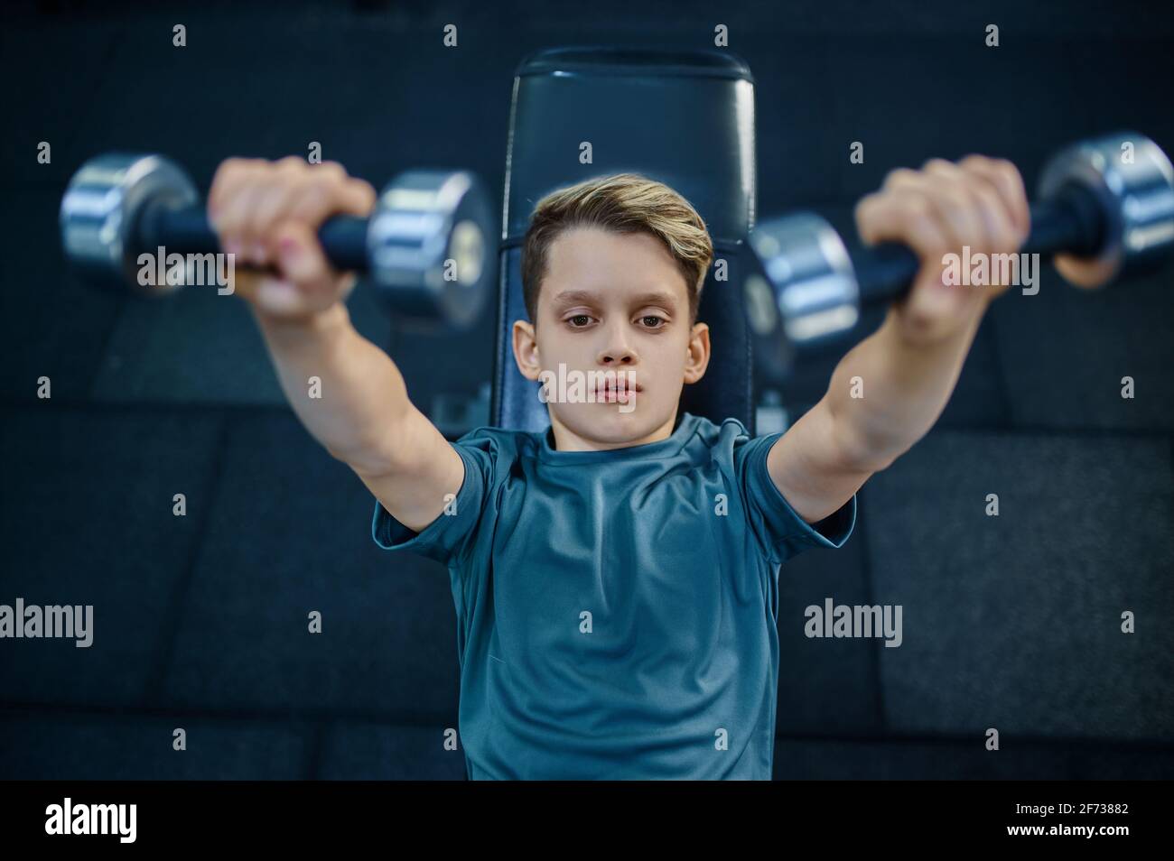 Boy doing exercise with dumbbells on bench Stock Photo - Alamy