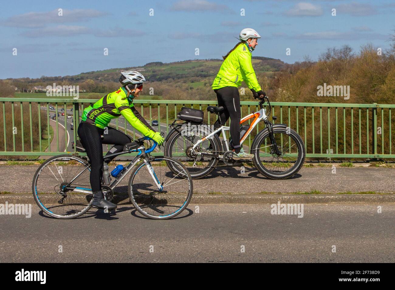 female cyclists riding sports road bikes on countryside route crossing ...