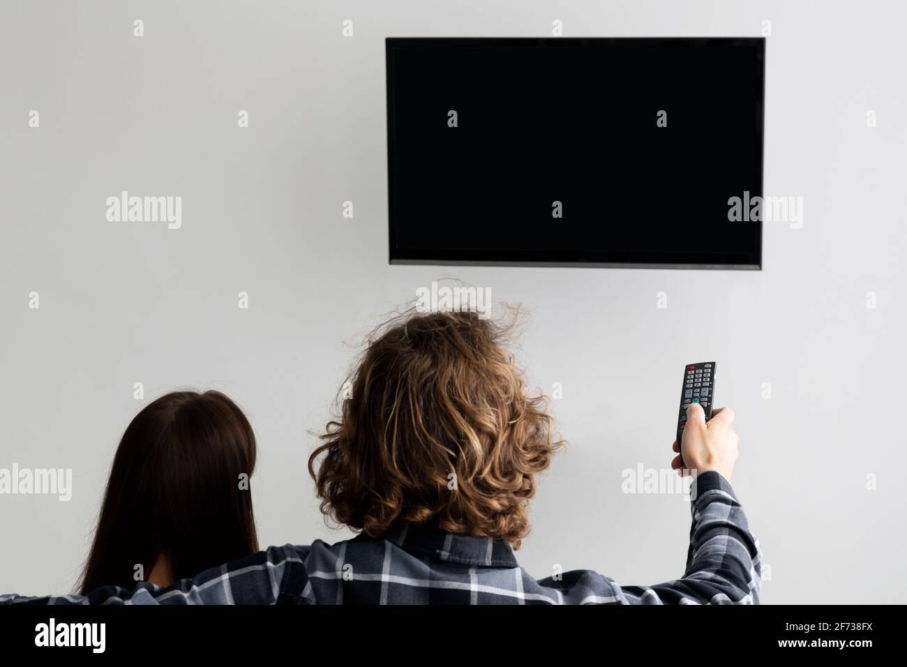 Couple Pointing Remote Control On Empty TV Screen Indoor, Back-View ...