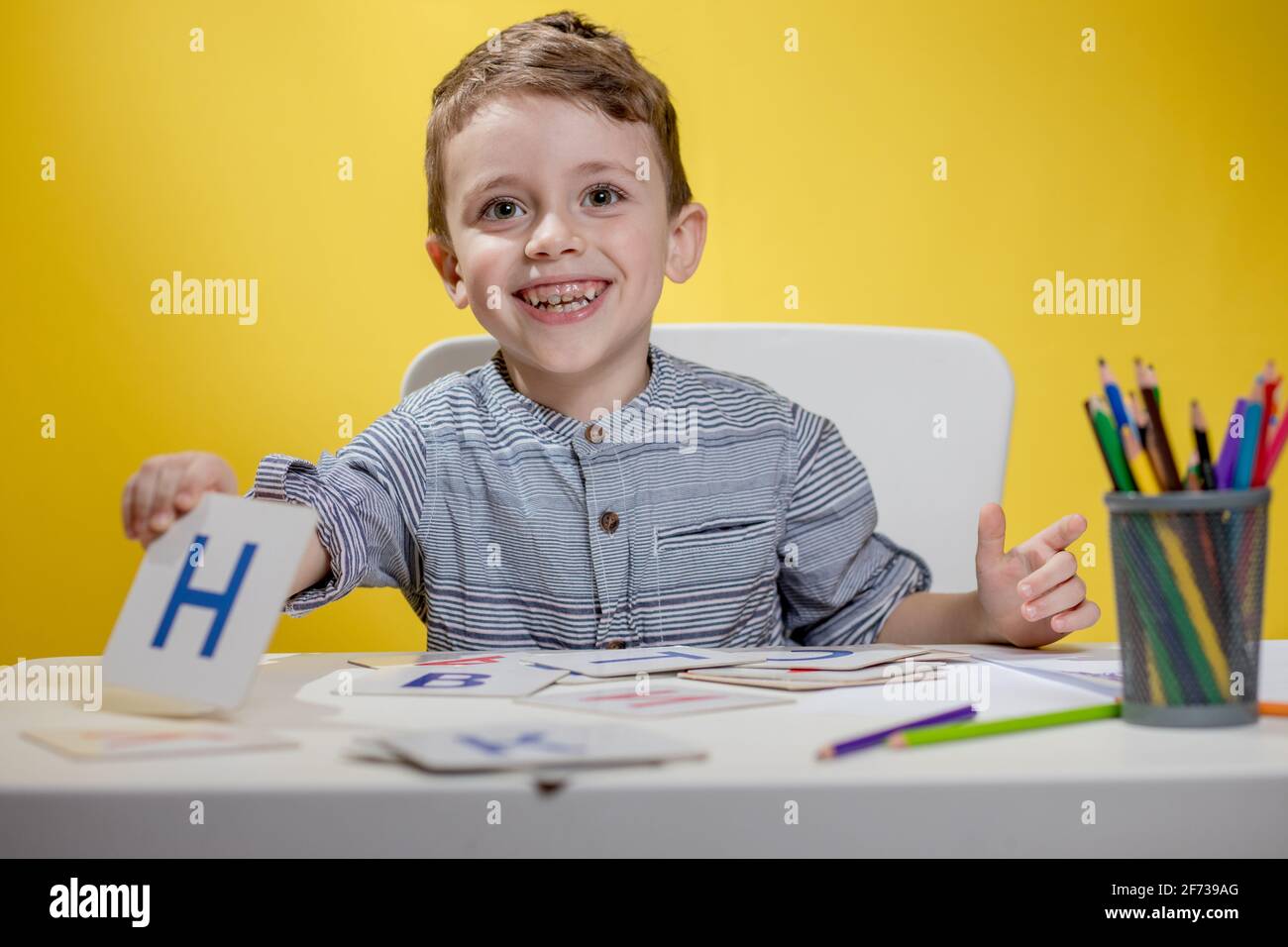 Happy smiling little preschool boy shows letters at home making ...