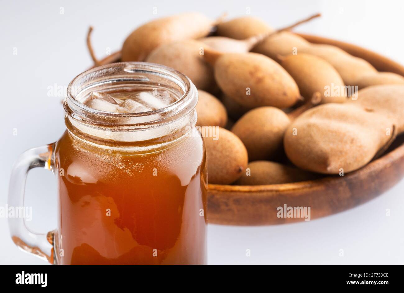Tamarindus indica - Tamarind juice in a glass surrounded by fresh ripe ...