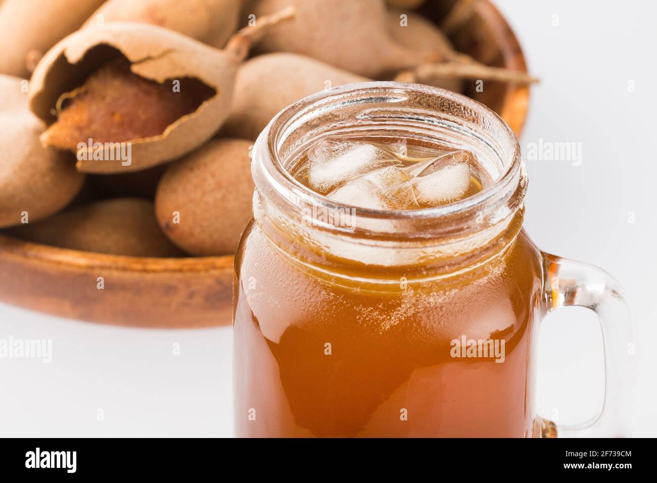 Tamarind juice in a glass surrounded by fresh ripe tamarinds ...