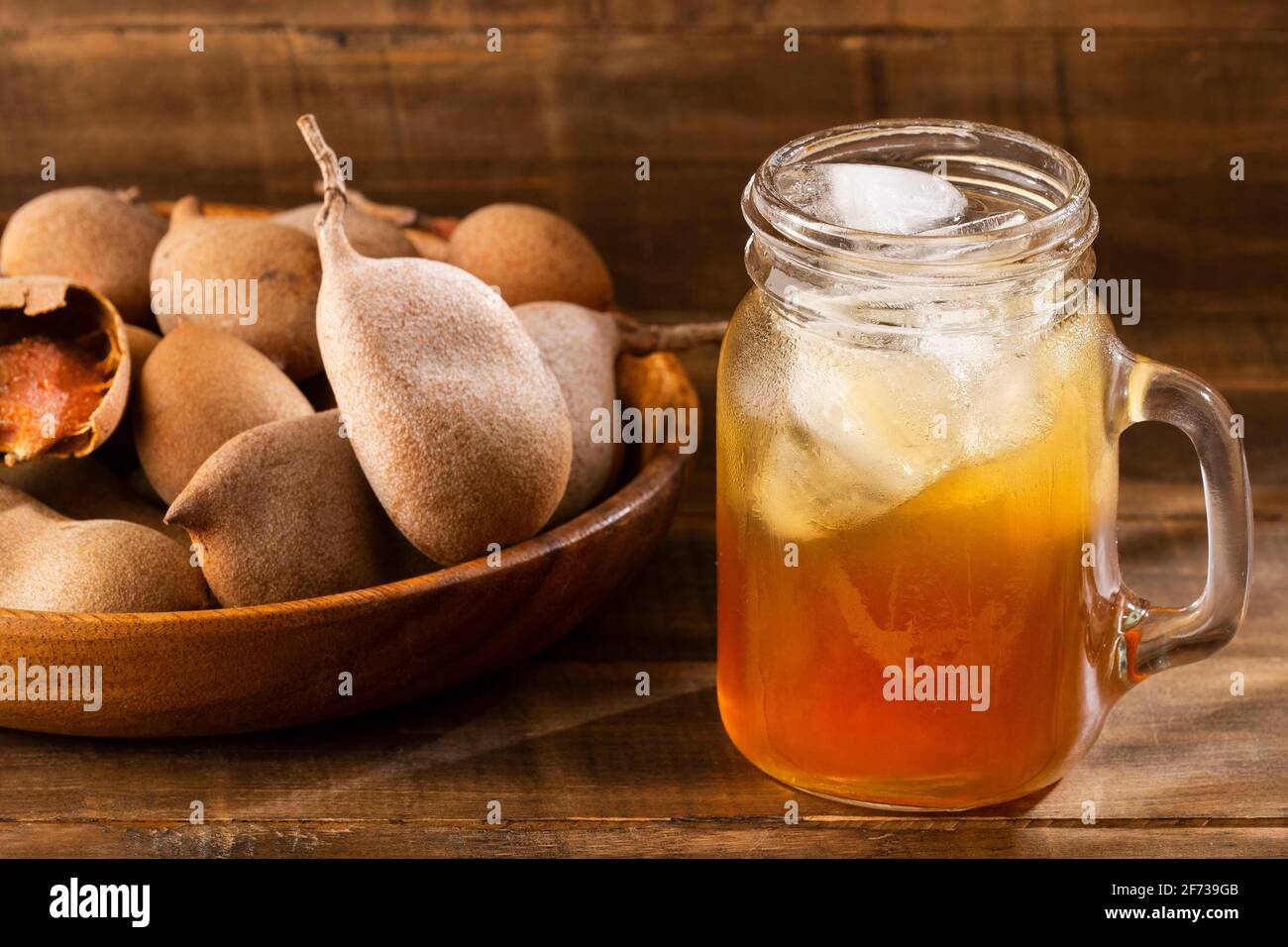 Delicious sweet drink, tamarind juice and ice on a rustic wooden table ...