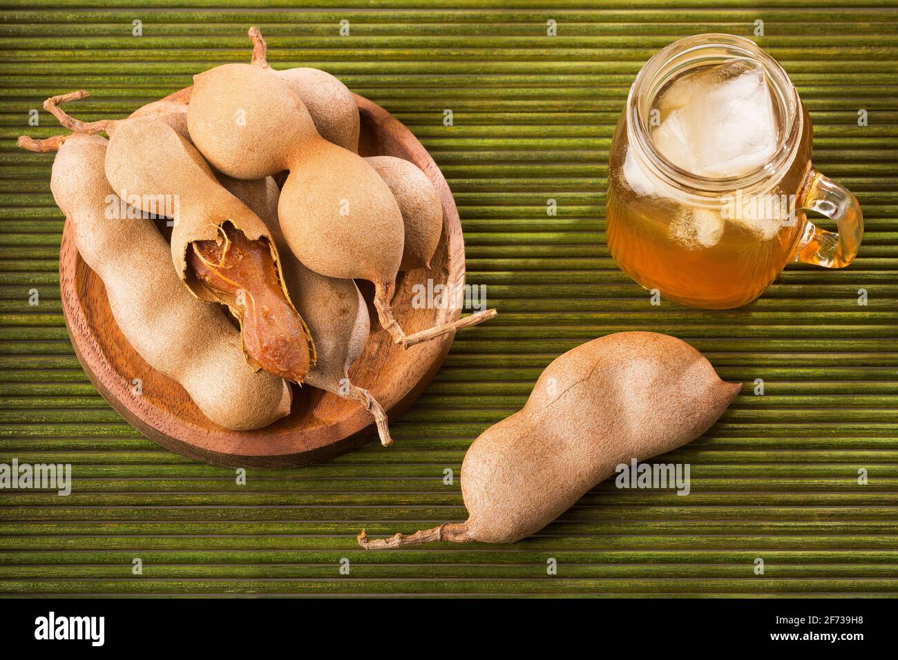 Tamarind juice in a glass surrounded by fresh ripe tamarinds ...