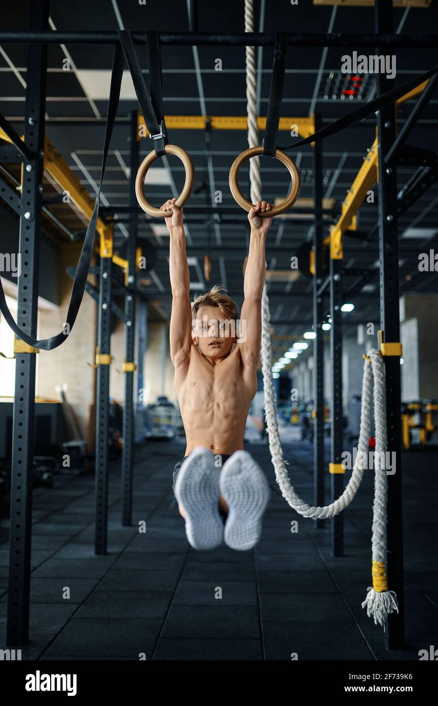 Boy doing exercise on rings in gym Stock Photo - Alamy