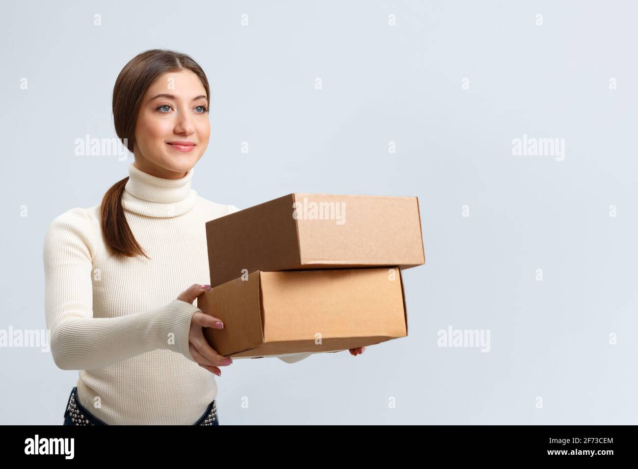 Smiling beautiful girl hands over boxes with orders. Young woman with ...