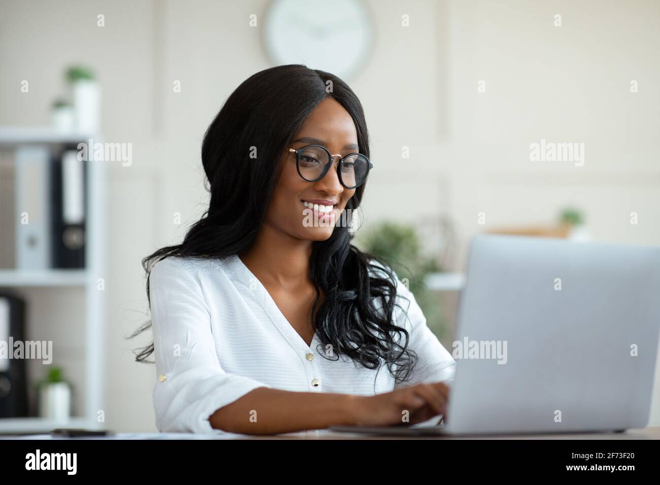 Happy female company worker using laptop pc and typing on keyboard at ...