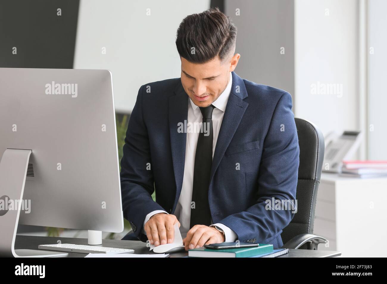 Young businessman cleaning computer in office Stock Photo - Alamy